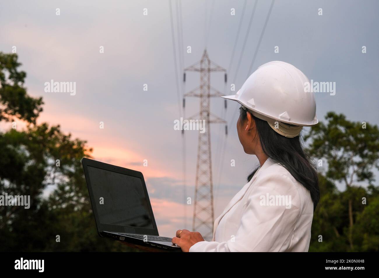 Asian female electrical engineer working on laptop near high voltage ...