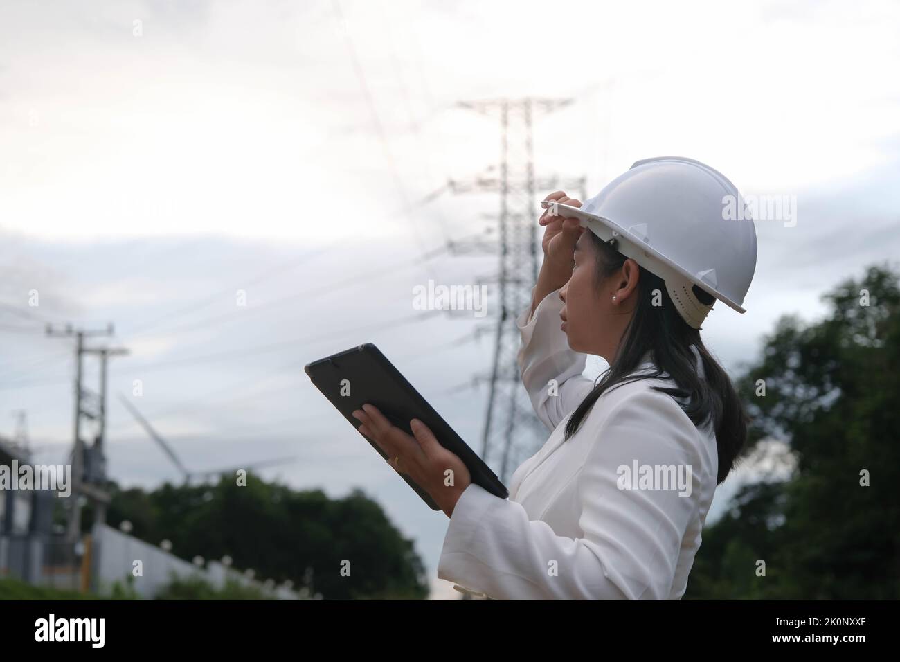 Asian female electrical engineer working on laptop near high voltage ...