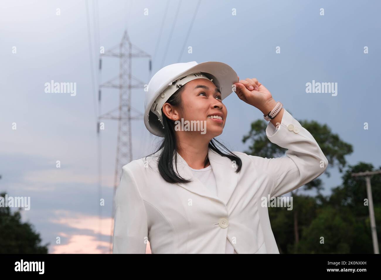 Asian female electrical engineer working near high voltage pole ...