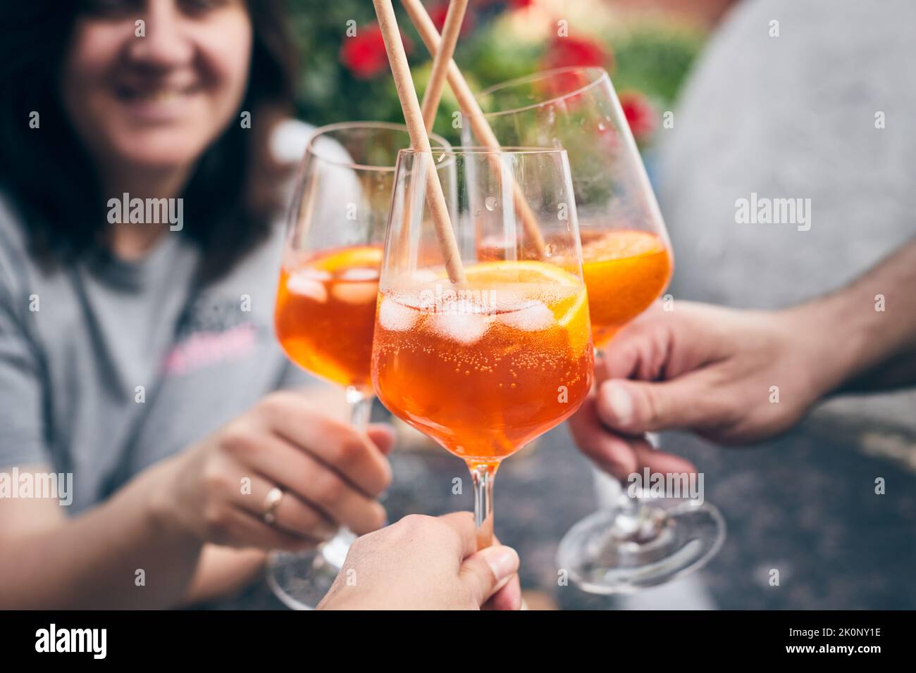 Friends raise glasses of Venetian Spritz at a home party. Front view ...