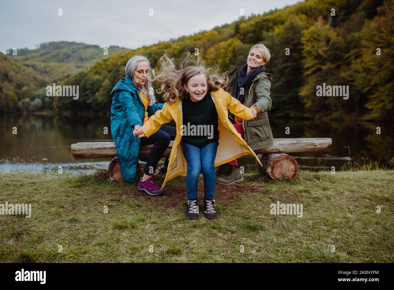 Small girl having fun, her mother and grandmother sitting on bench ...