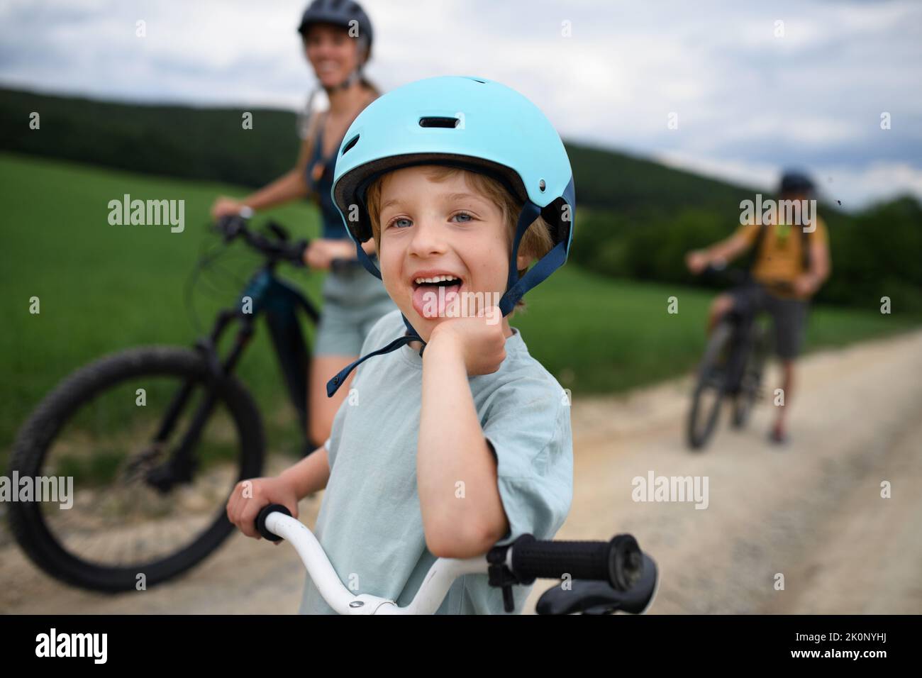 Portrait of excited little boy with his family at backround riding bike ...