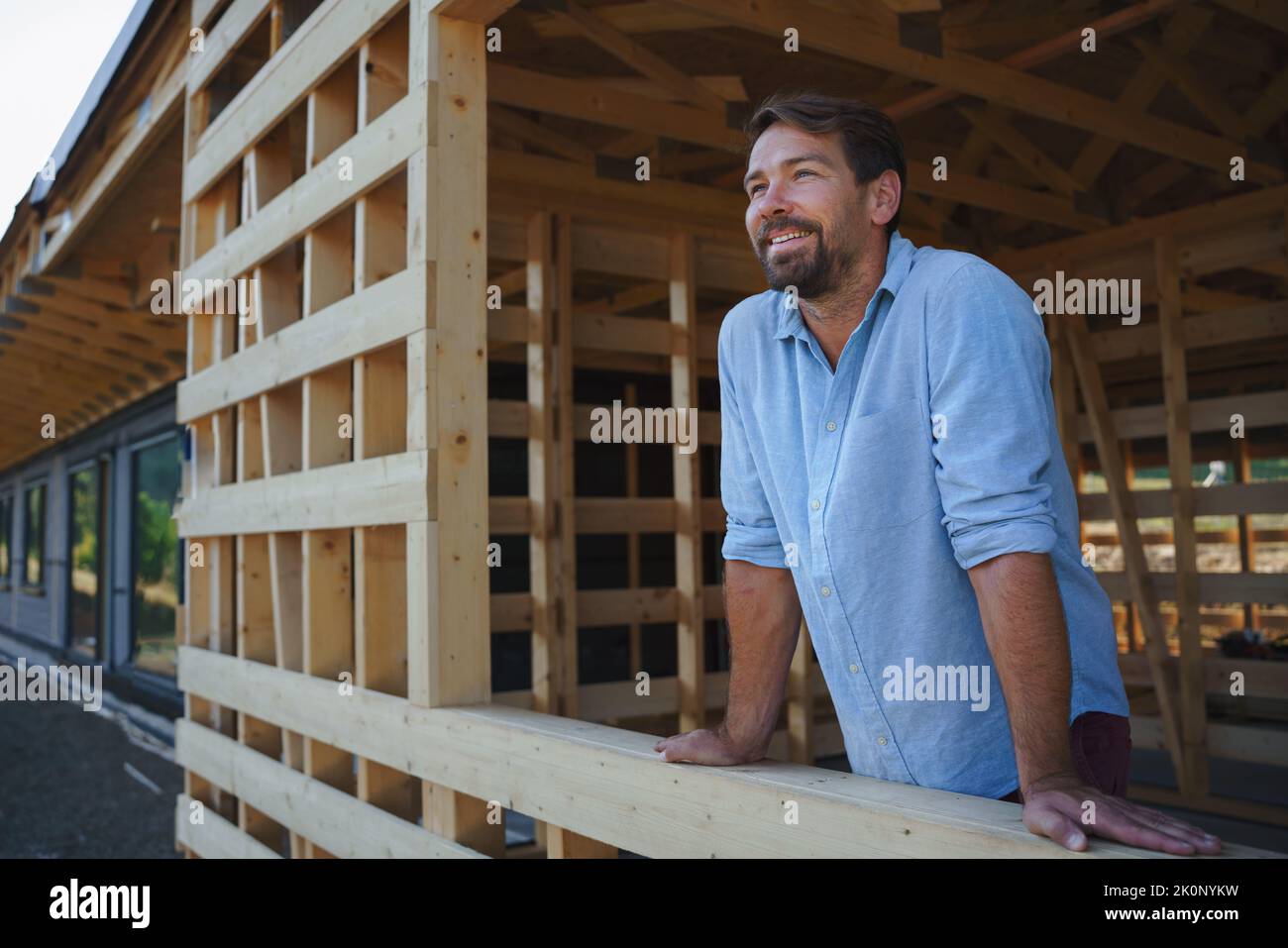 Man looking out of his unfinished house, construction of ecological ...