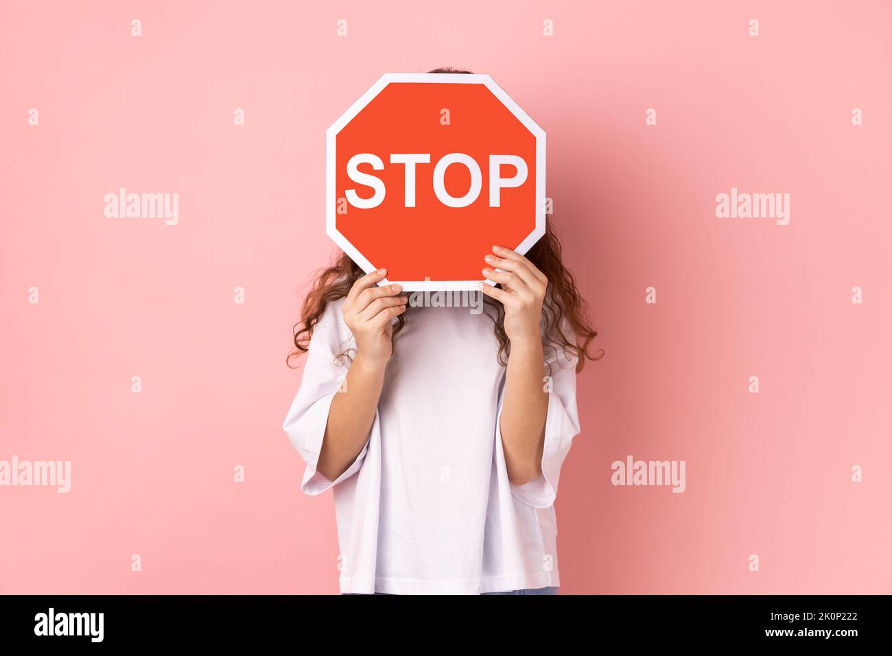 Portrait of anonymous little girl wearing white T-shirt covering face ...