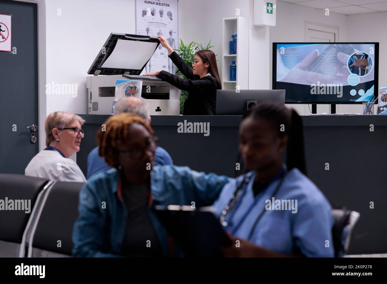 Female secretary working with copy printer at hopital reception desk to ...