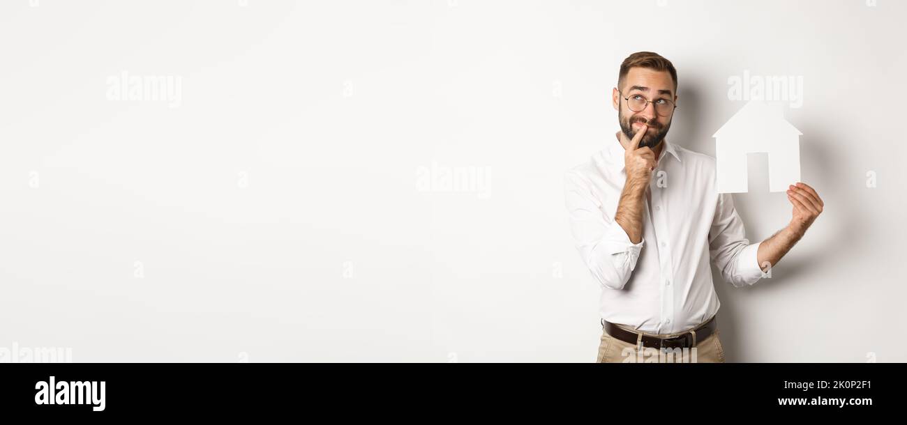 Real estate. Man thinking while searching for apartment, holding paper ...