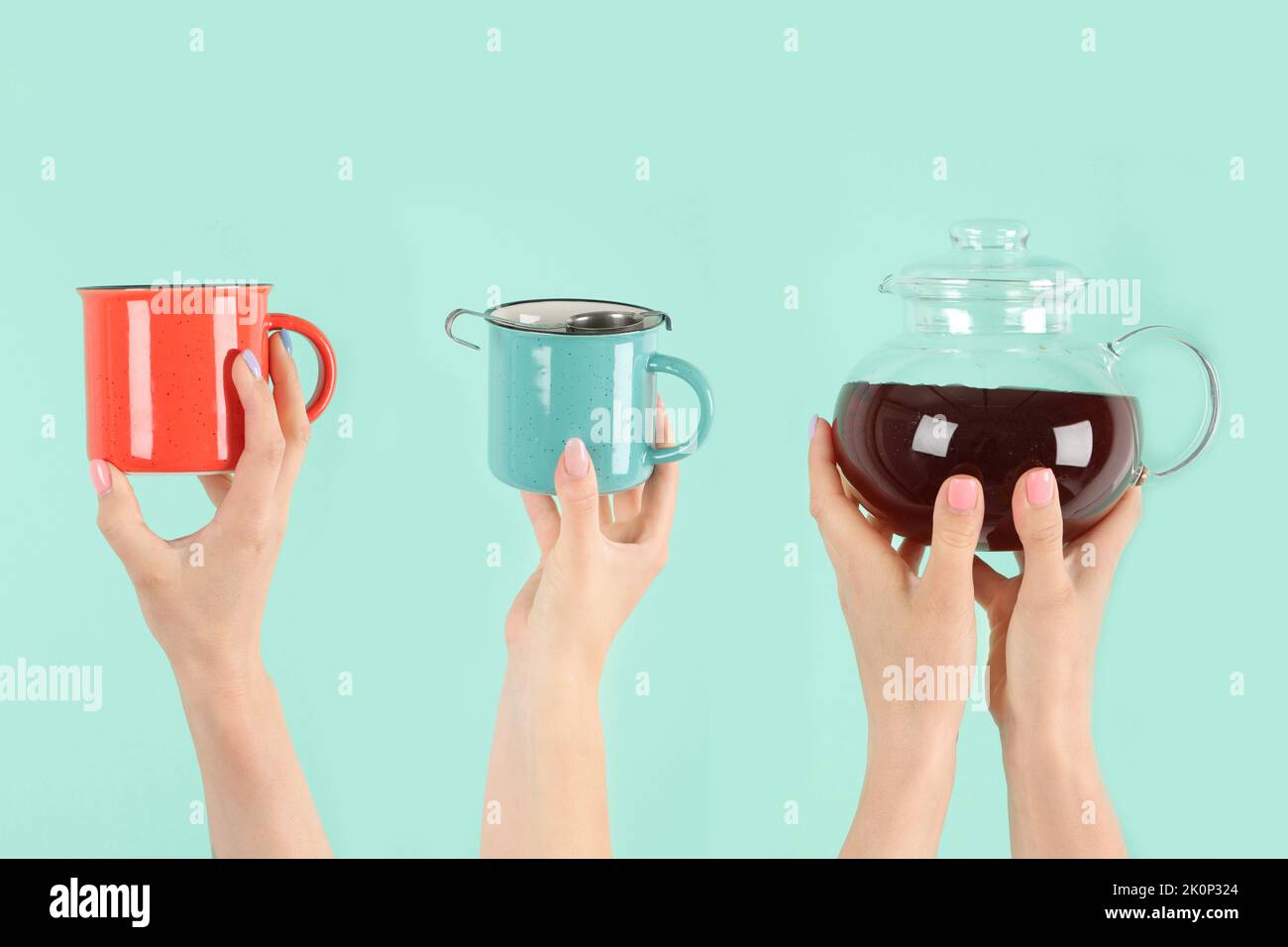 Arms raised up holding tea cup on green background. Concept photo ...