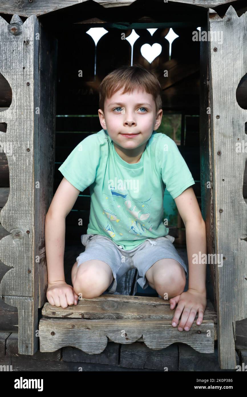 Portrait of child in window opening of wooden house Stock Photo - Alamy