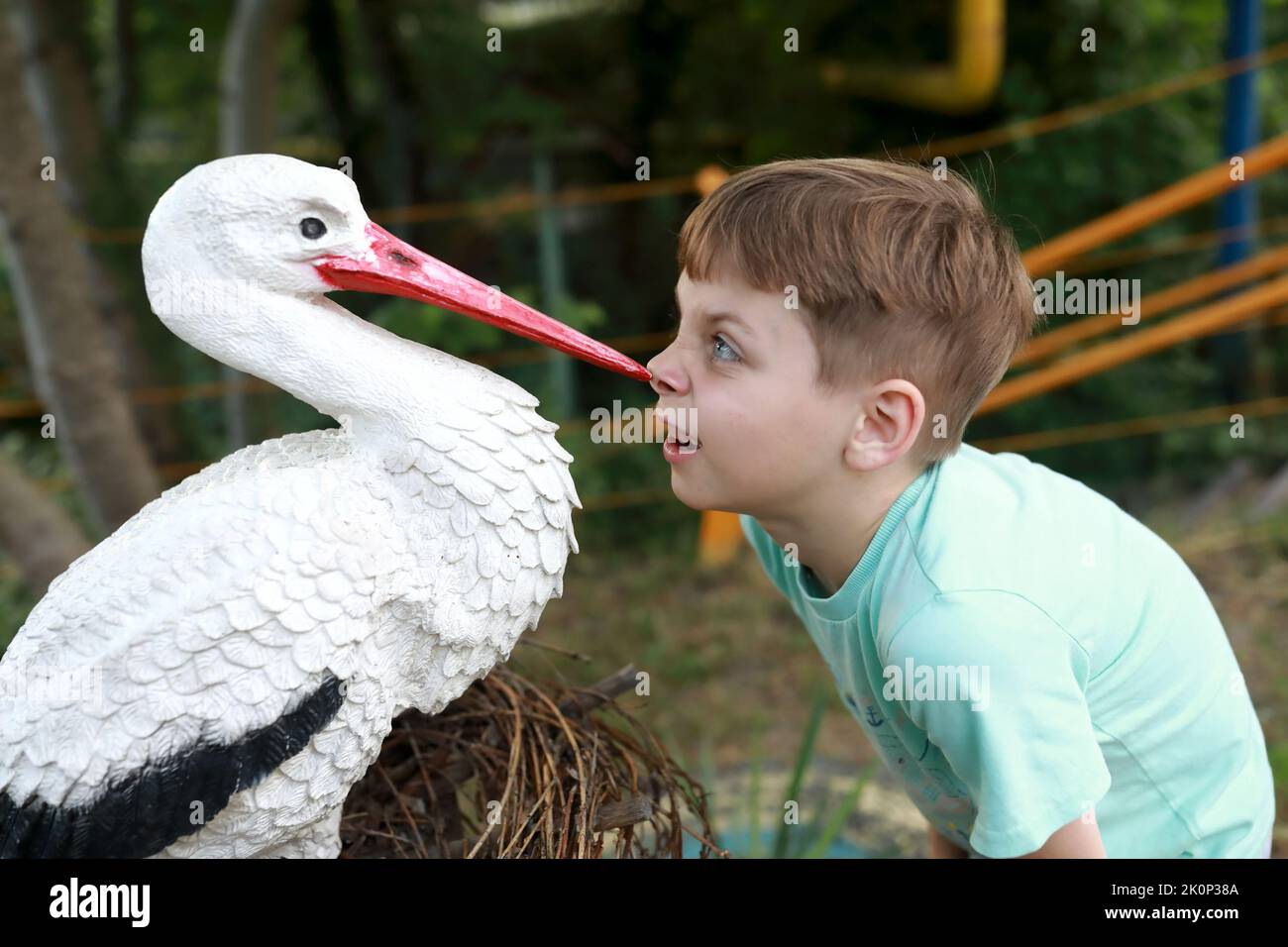 Child touching beak of statue of goose with his nose in park Stock ...