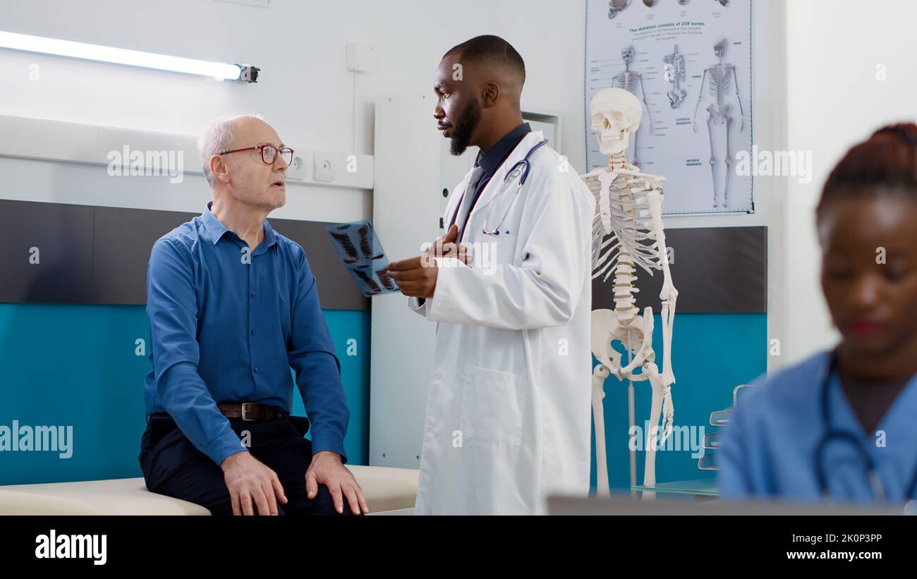 Male physician showing radiography scan to sick patient, explaining ...