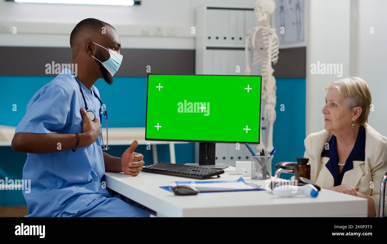 Male nurse and woman with impairment analyzing greenscreen display on ...