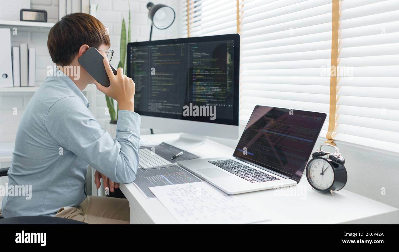 Software development concept, Male programmer talking on smartphone and check data code on ...