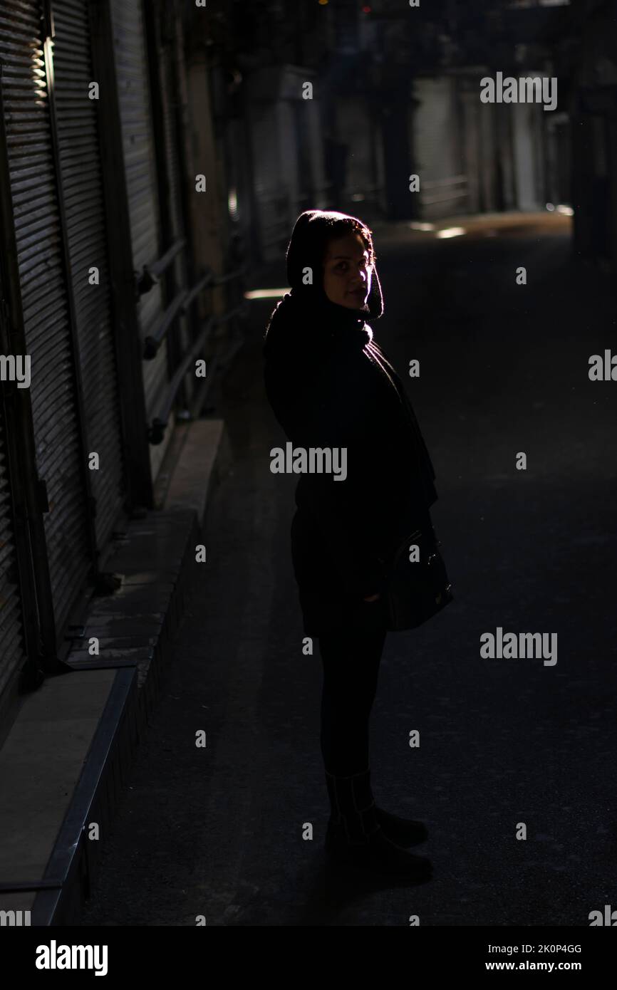 Young woman standing in dark alley Stock Photo - Alamy