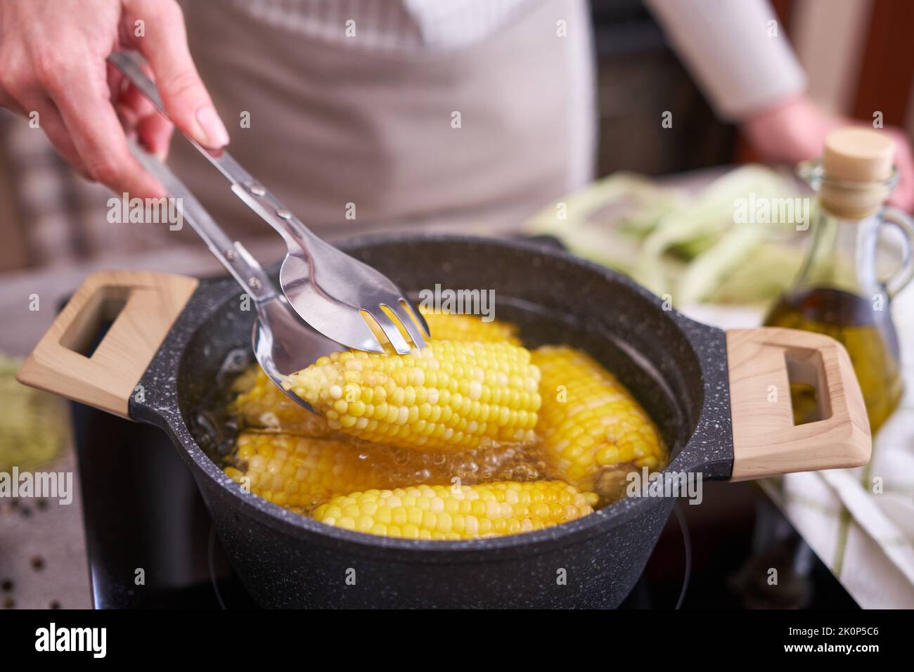 Cooking corn cob in a pot of boiling water with bubbles Stock Photo - Alamy