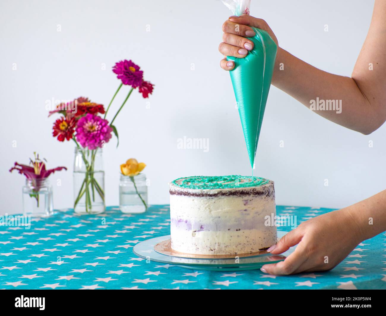 hands level the cream with a pastry bag and cover the round cake Stock ...