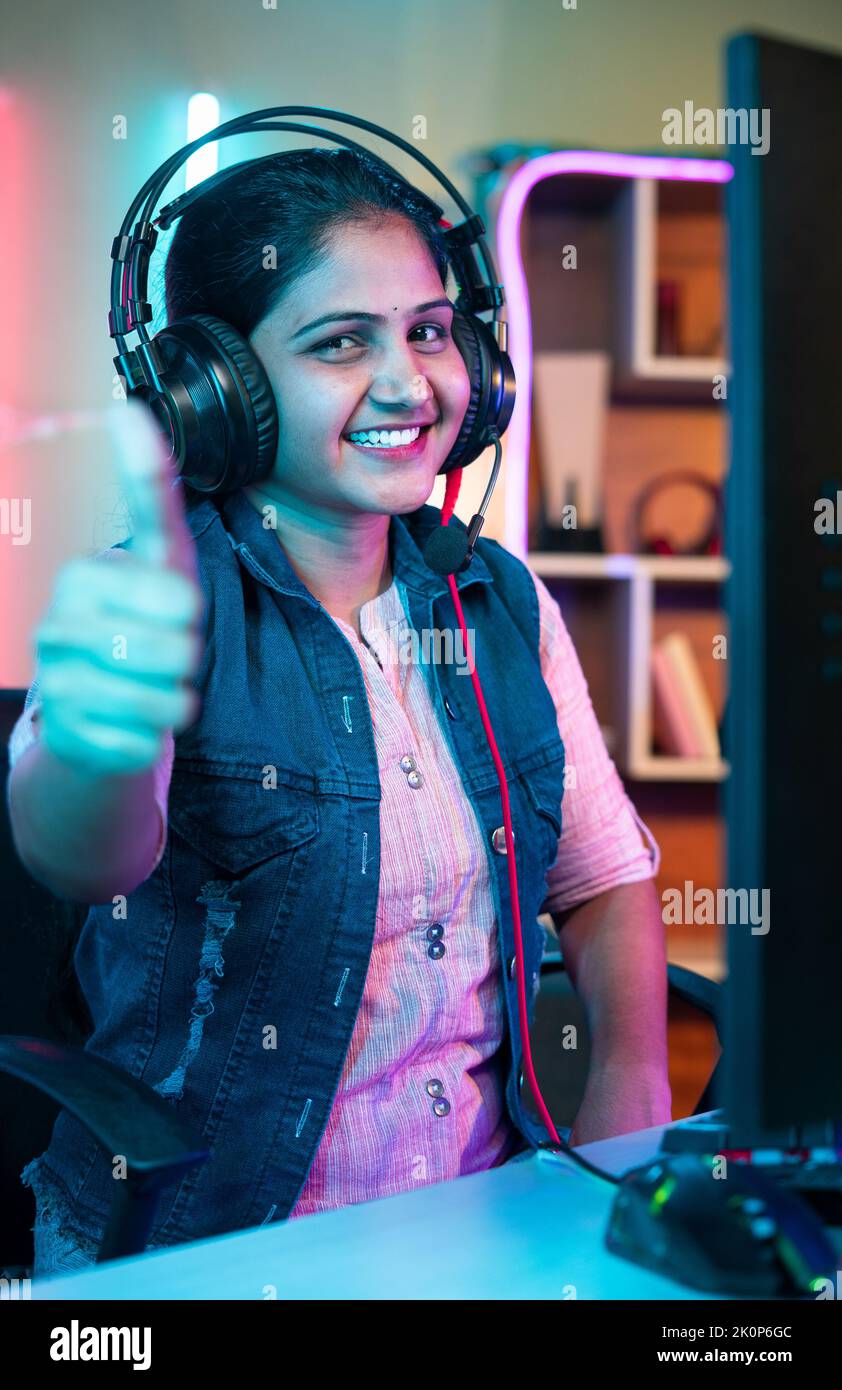 vertical shot of Smiling gamer showing thumbs up while playing online ...