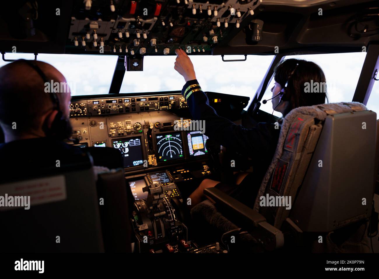 Team of aircrew member and captain using power switch on cockpit ...