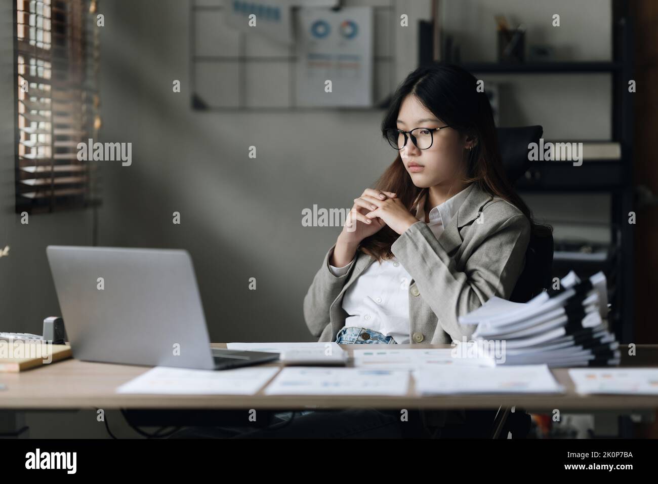 Stressed Asian business woman worry with many document on desk at ...