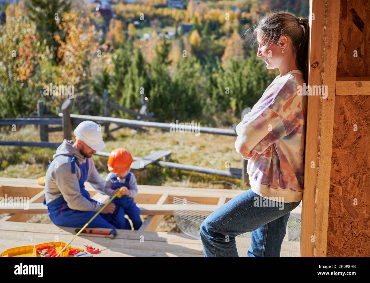 Father, mother and son building wooden frame house. Toddler boy helping ...