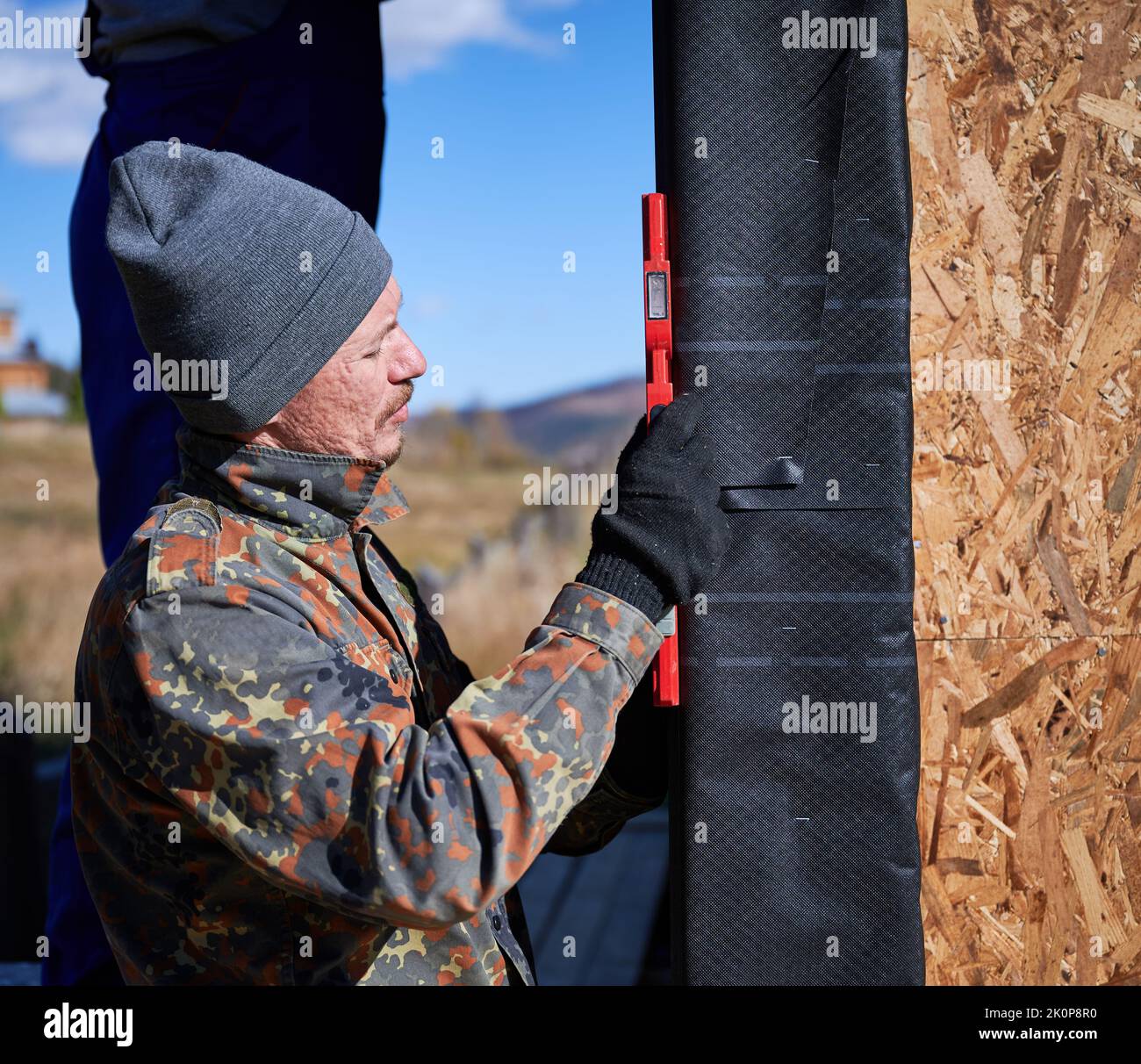 Male builders using red spirit level and measuring vertical surface of ...