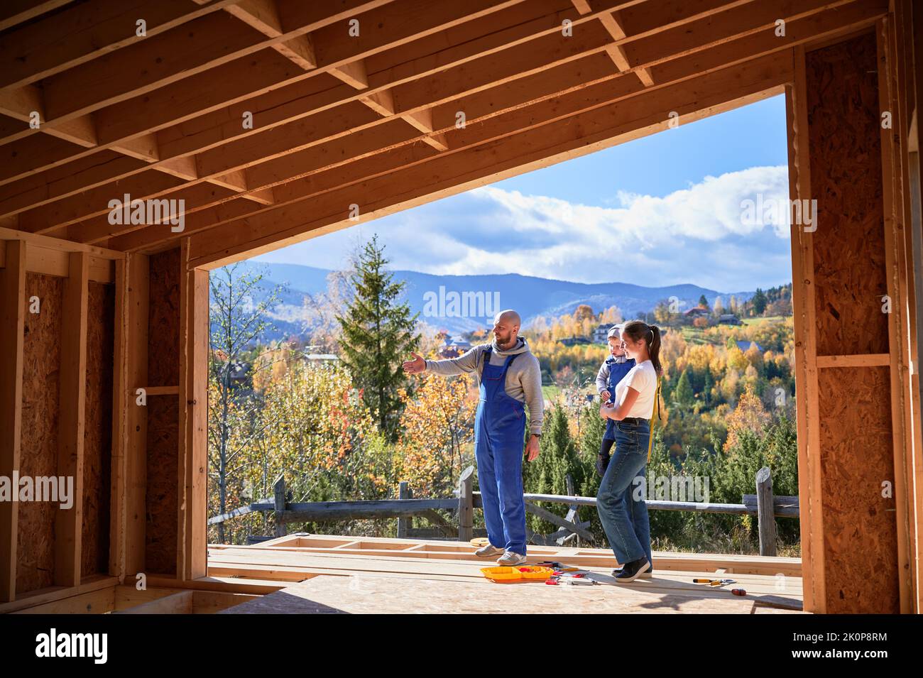 Father, mother and son building wooden frame house in the Scandinavian ...