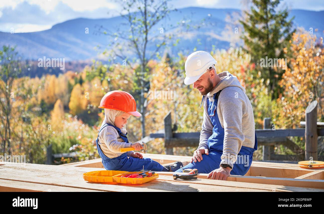 Father with toddler son building wooden frame house. Male builders ...
