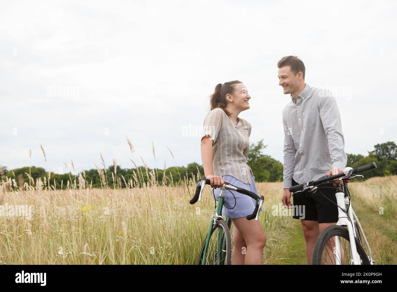 The happy couple cycling near the field. Cyclists man and a woman with ...