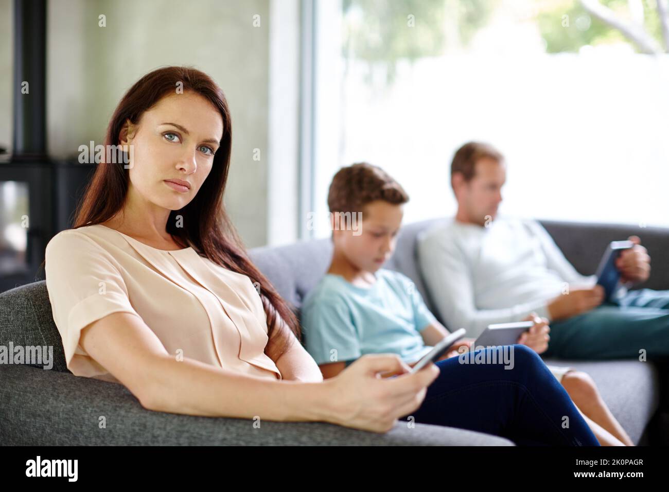 Technology is separating us. a family of three sitting separately on a ...
