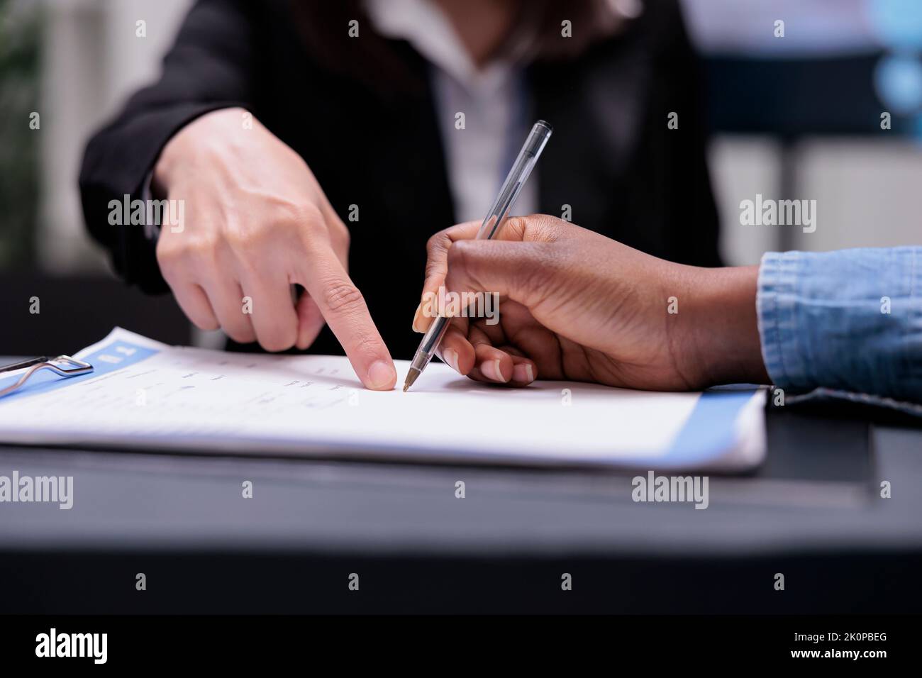 Patient filling in report papers at reception desk, signing ...
