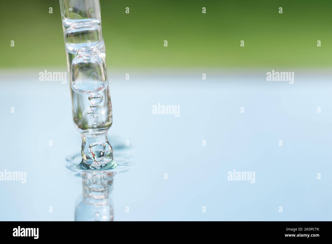 Pipette with transparent cosmetic liquid against blue and green ...