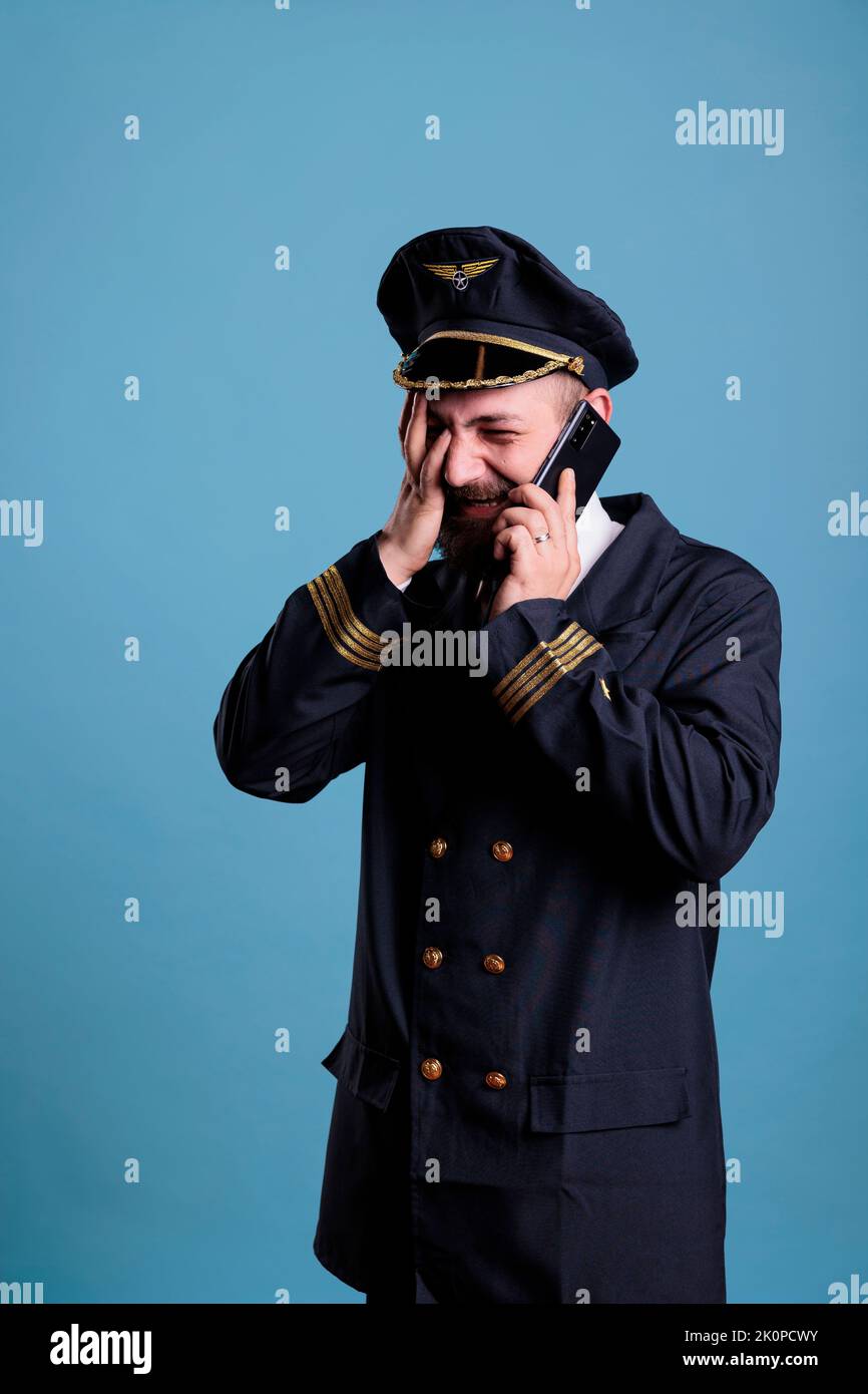Middle aged pilot talking on smartphone with face palm expression ...