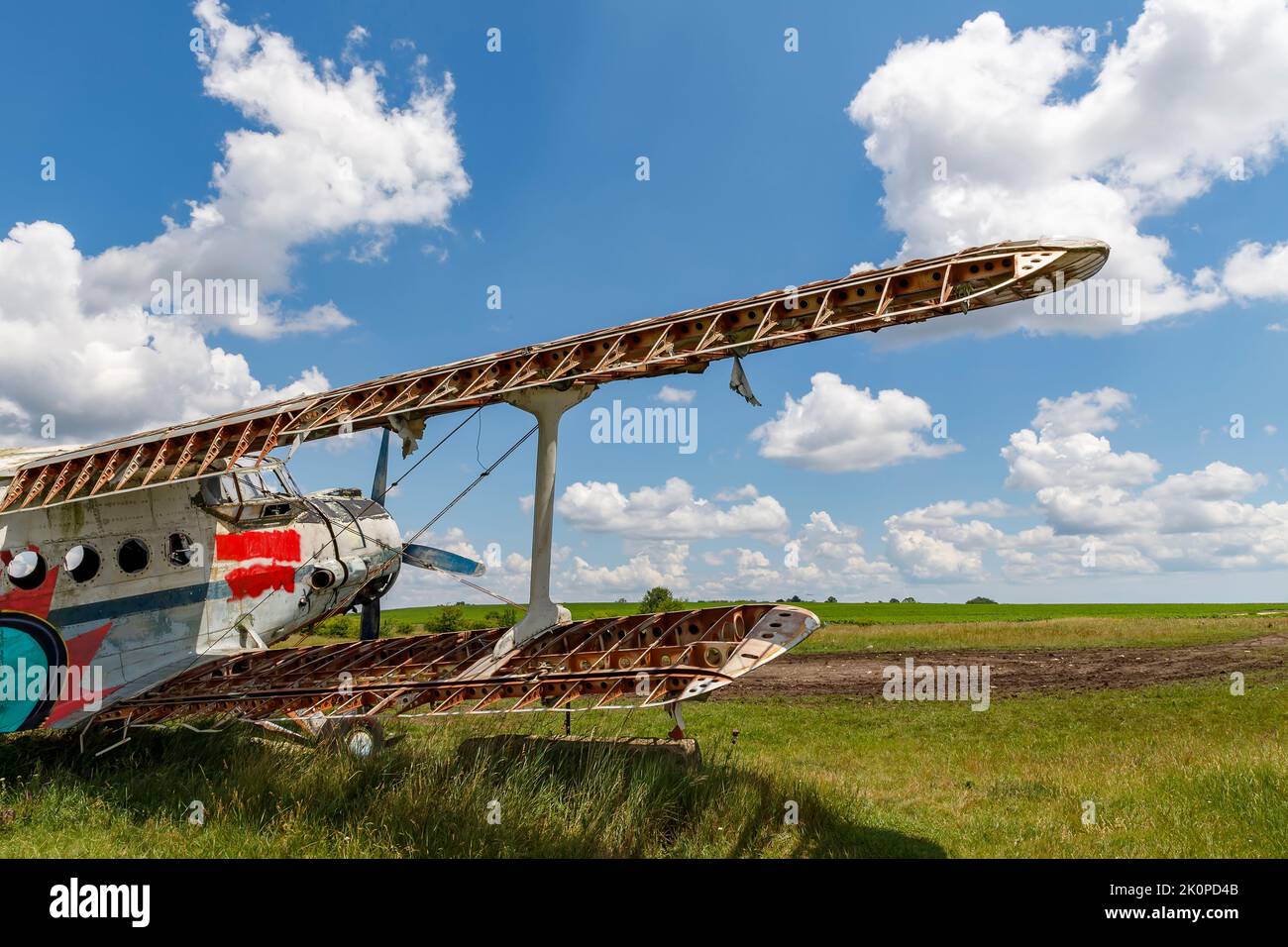 Abandoned aircraft plane standing in the field against the cloudy blue ...