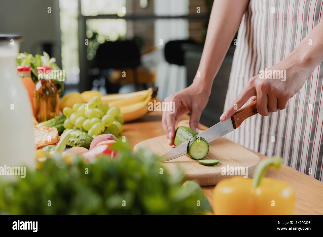 Close up on young housewife woman or girl hands slicing cucumber with ...