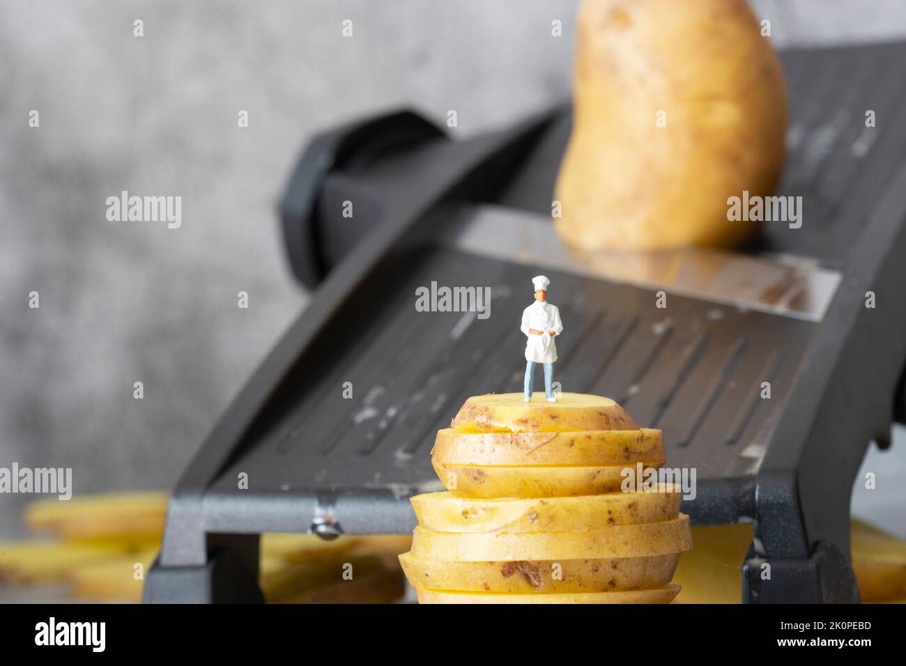 Miniature scale model chef, standing on stacked potato, with kitchen ...