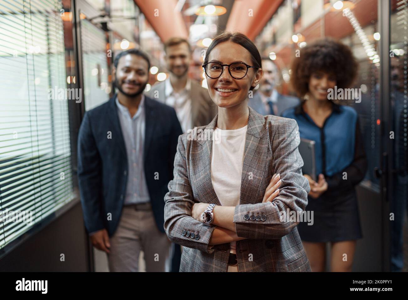 Portrait of smiling businesswoman in glasses standing in modern office ...
