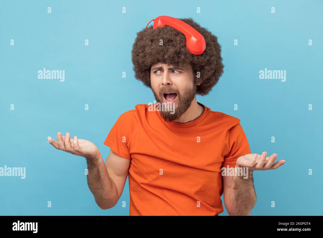 Portrait of confused puzzled man with Afro hairstyle in orange T-shirt ...