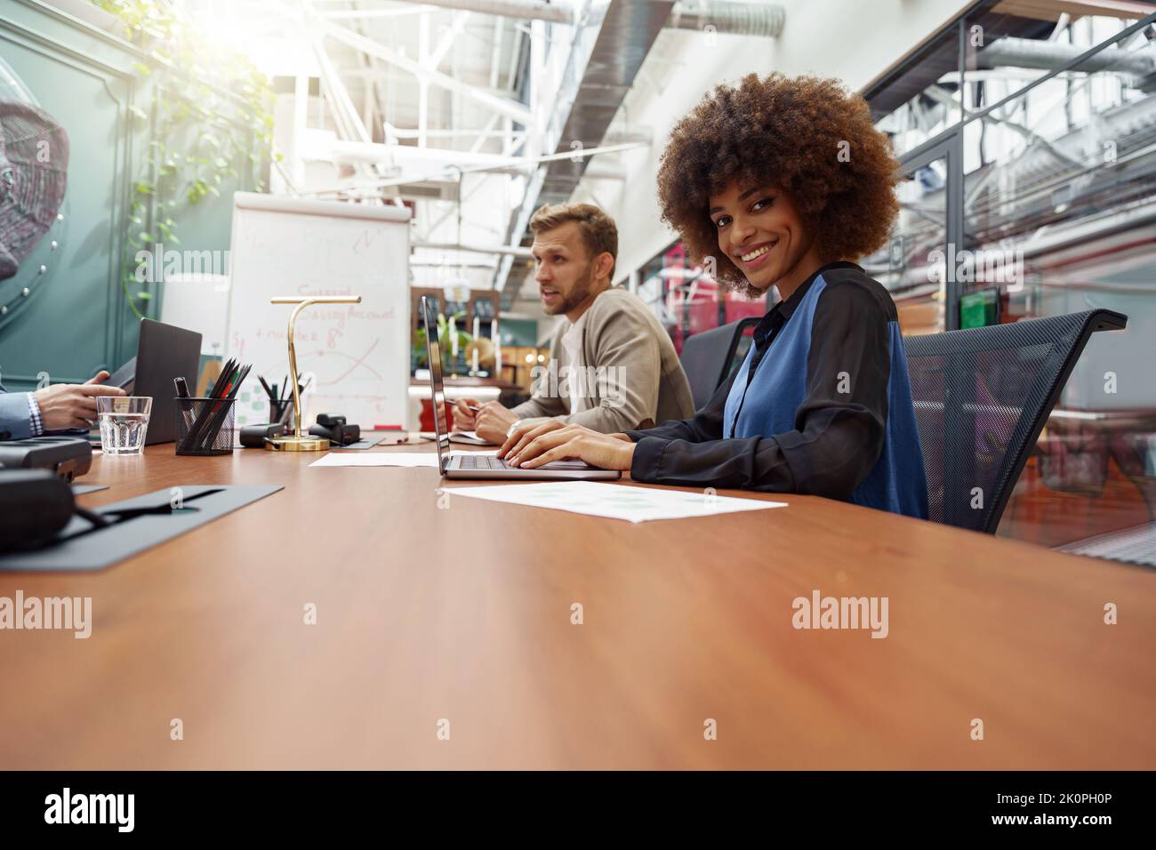 Smiling african businesswoman sitting on his workplace in modern office ...