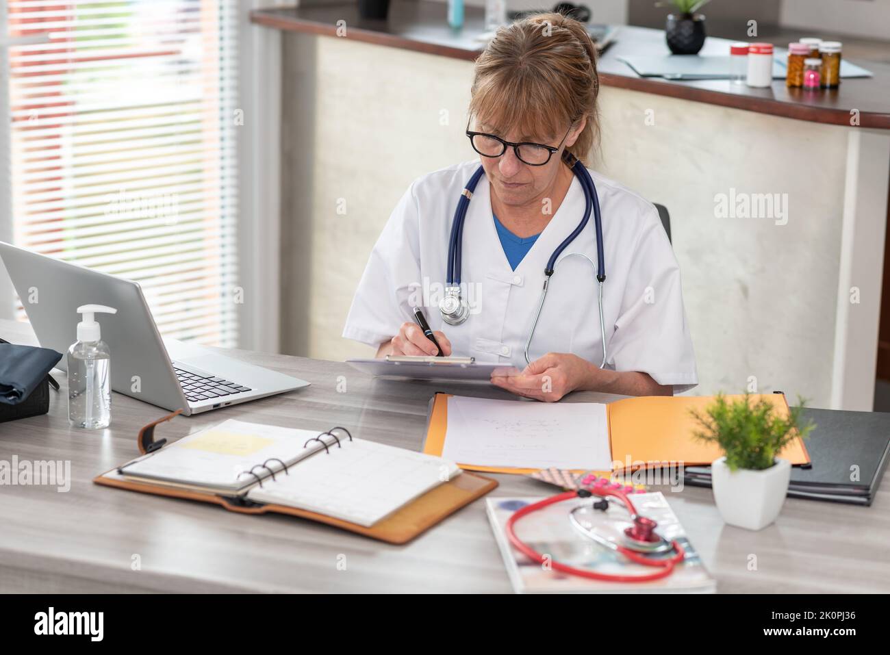 Female doctor taking notes on clipboard in medical office Stock Photo ...