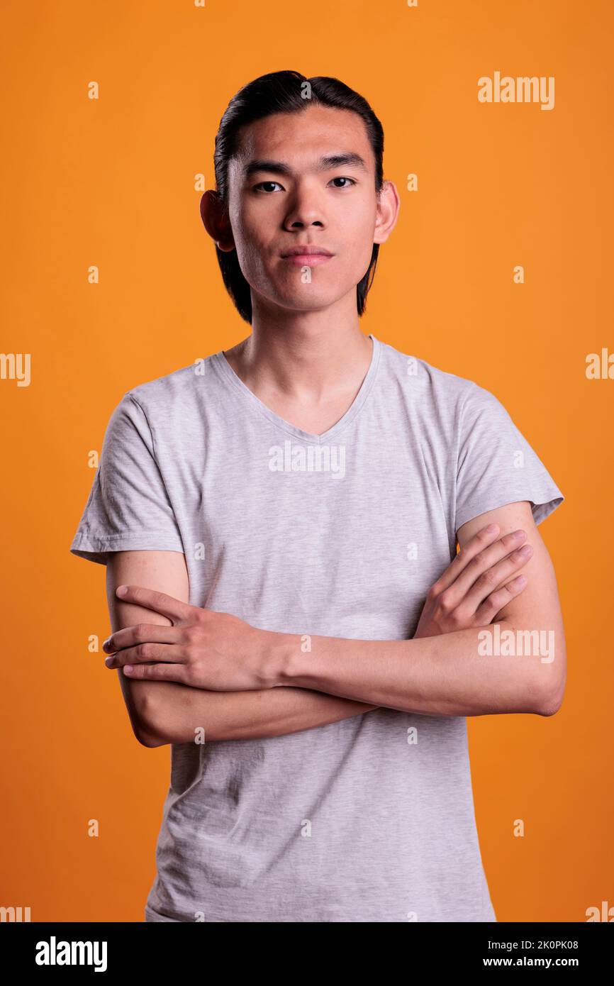 Serious young asian man standing in confident pose with arms crossed ...