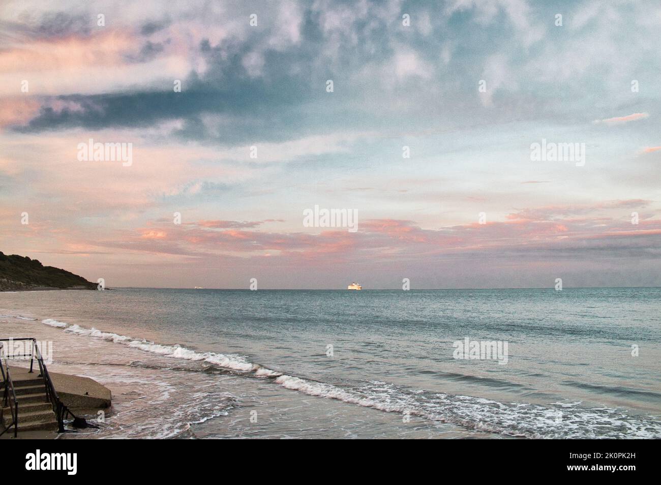 A view of the sandy shore before the seascape under the cloudy sunset ...