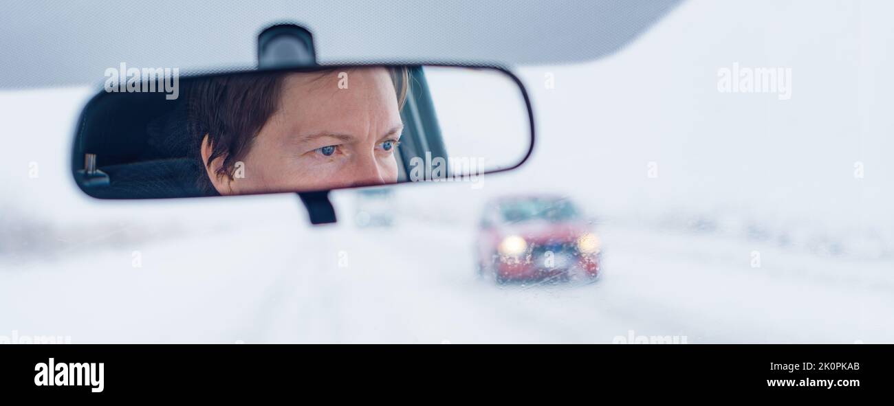 Face of a female driver in car rear-view mirror while driving in bad ...