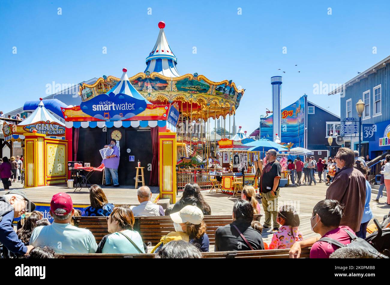 A magician performs a magic show on a stage in front f a carousel on ...