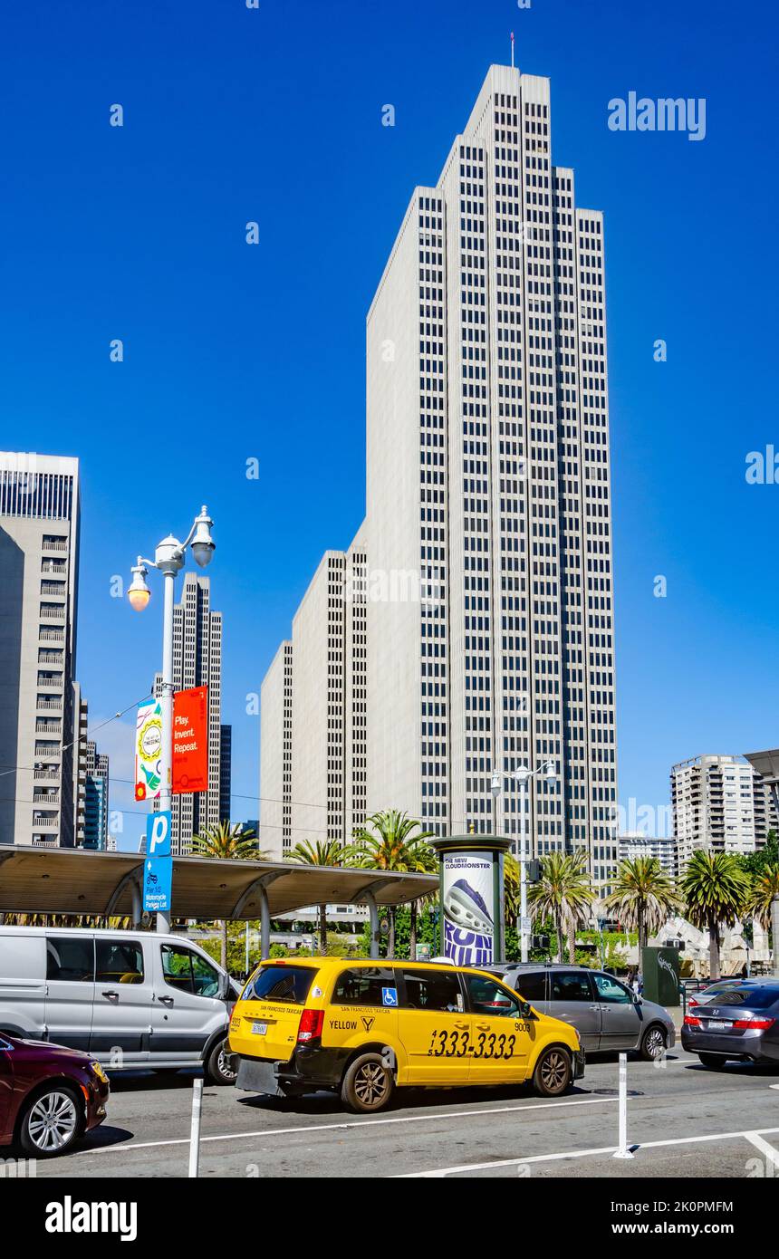 A yellow taxi in traffic on Embarcadero Street in San Francisco at a a ...