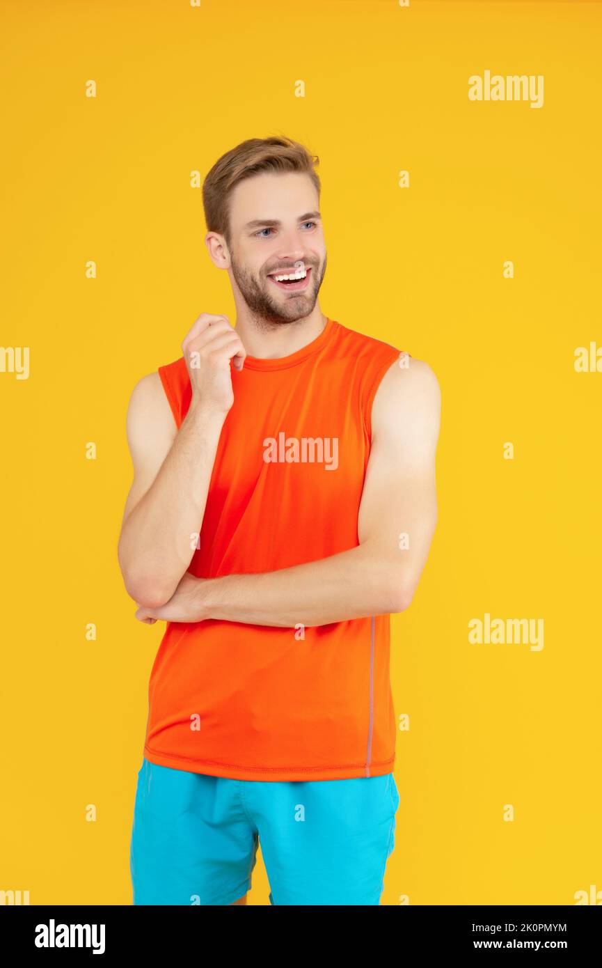 Athletic man looking aside. Happy sportsman isolated on yellow ...