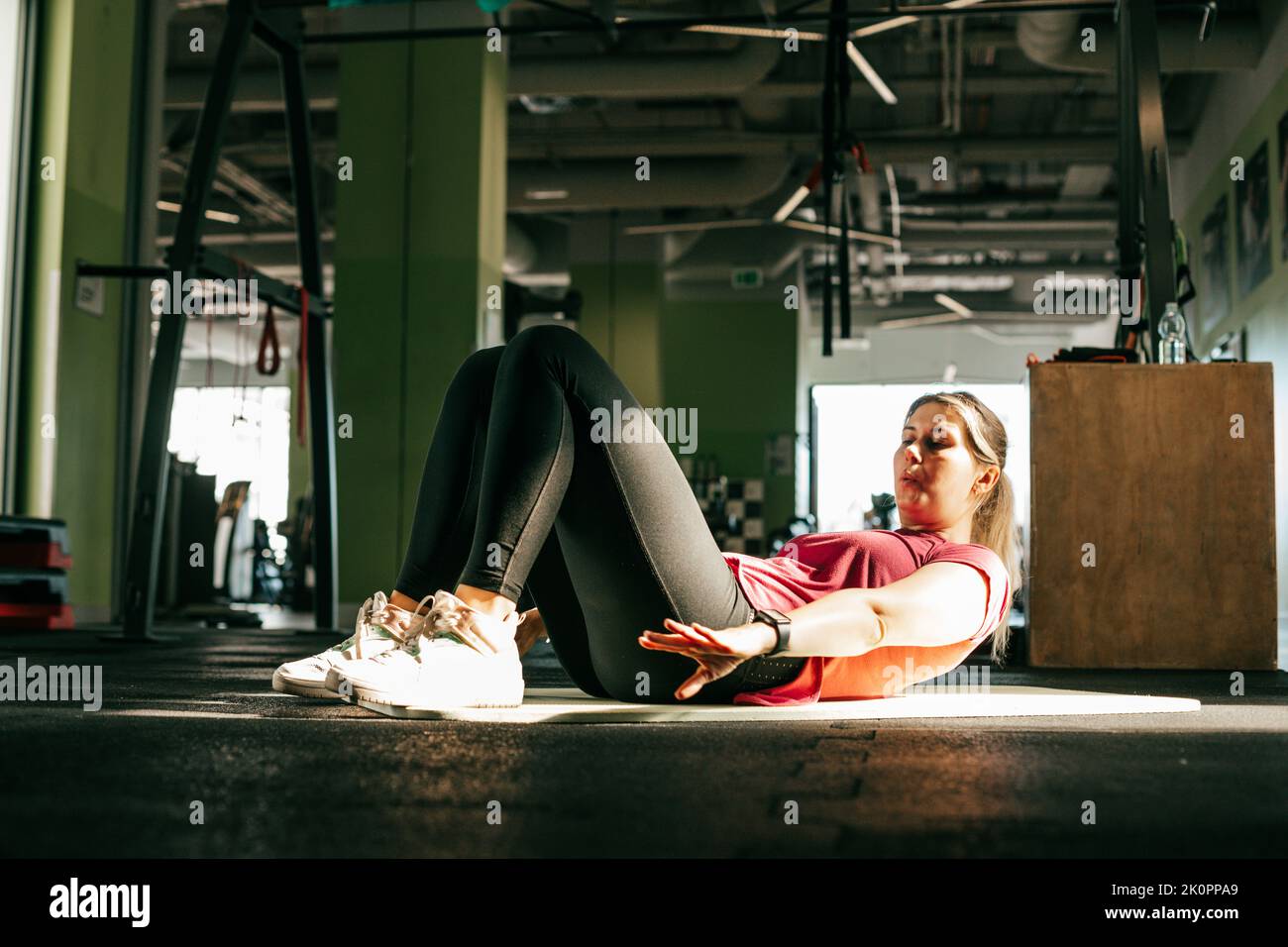 Overweight girl pump press in fitness gym lying on mat with bent knees ...