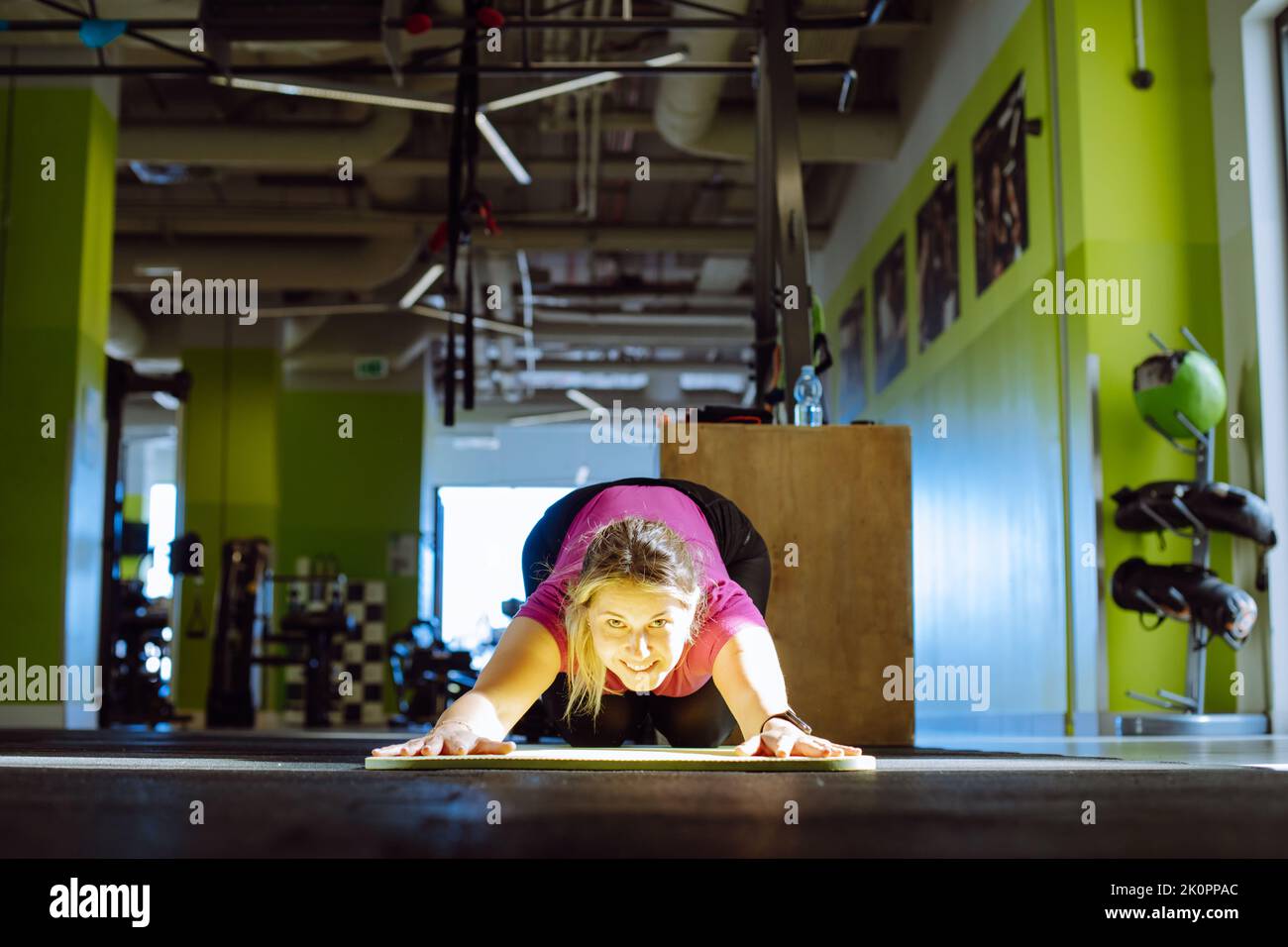 Joyful girl lie on knees leaning forward with outstretched arms on mat ...