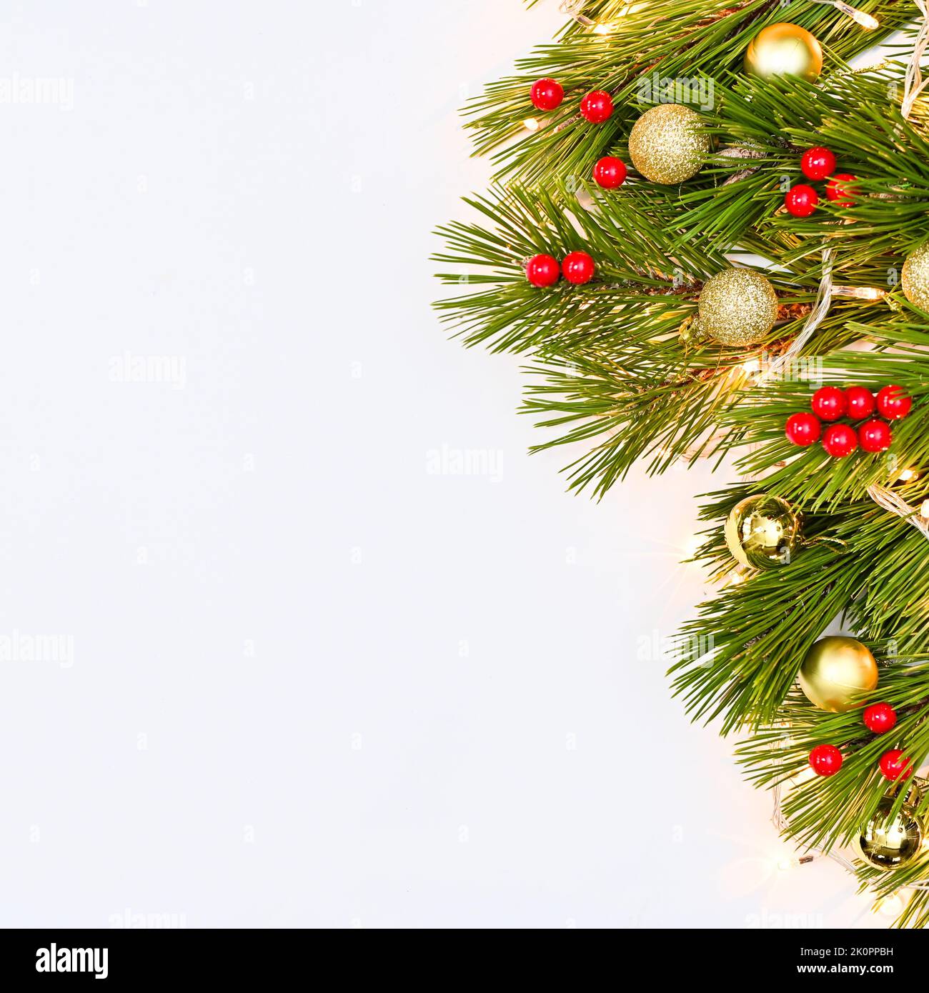 Pine branches decorated with red and gold ornaments on white copy space ...