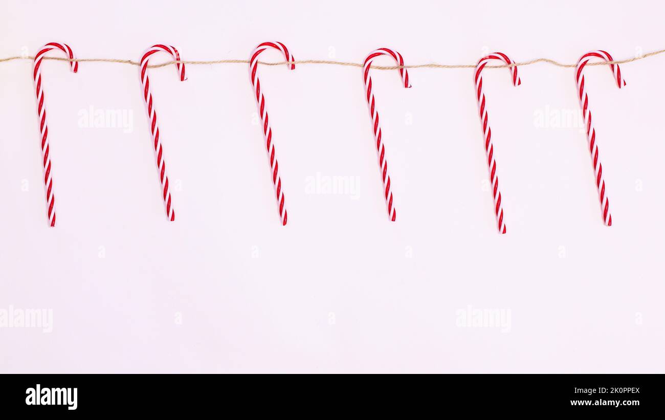 Christmas candy canes hanged on rope on white background with copy ...