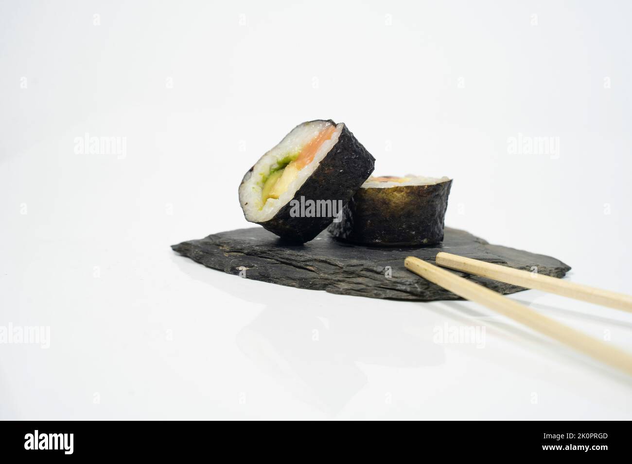 a piece of shushi with chopsticks in white background Stock Photo - Alamy