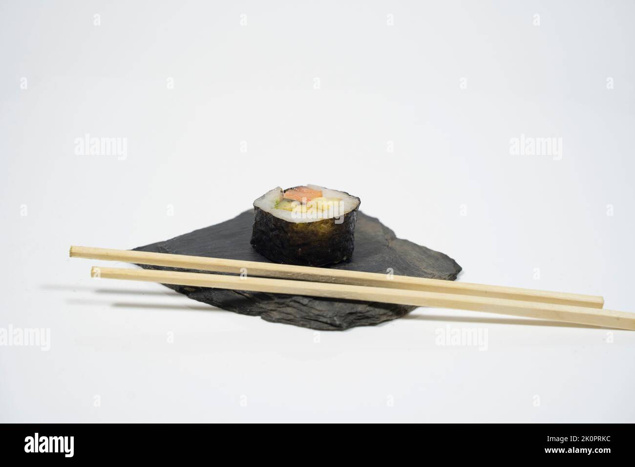 a piece of shushi with chopsticks in white background Stock Photo - Alamy